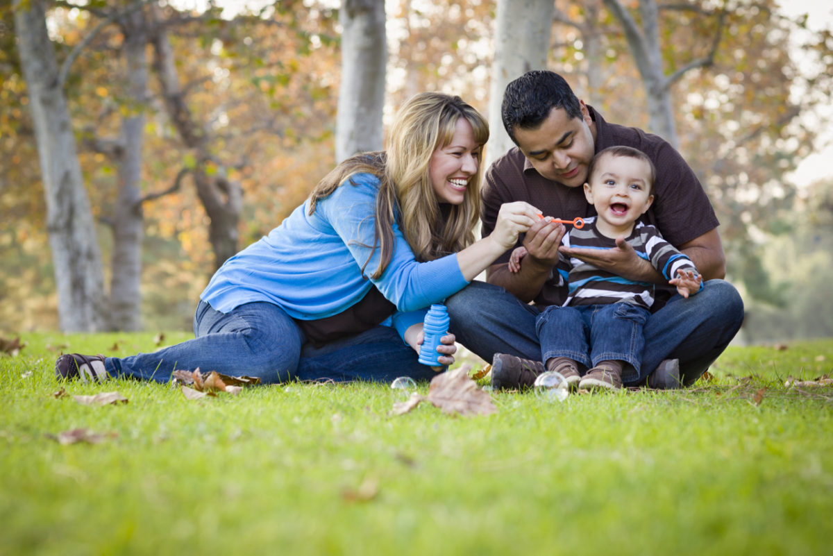 Happy Mixed Race Ethnic Family Playing with Bubbles In Park - Shaping ...
