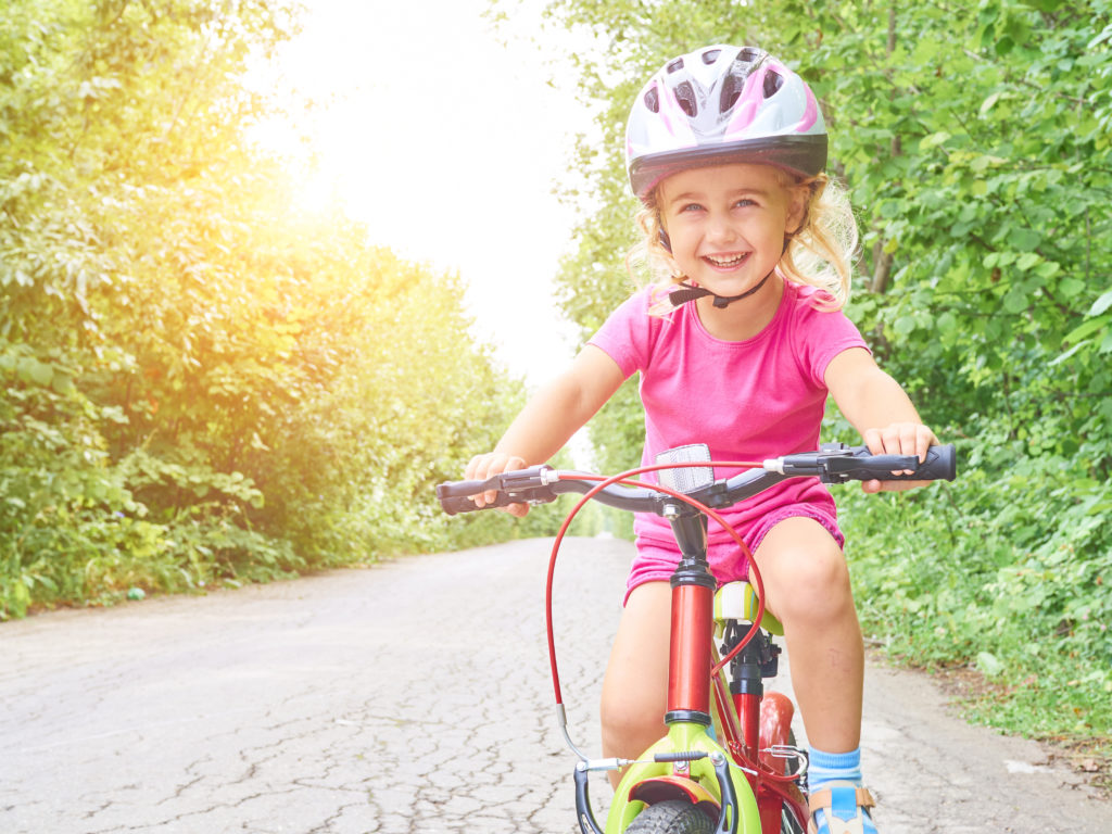Happy child riding a bike in outdoor. - Shaping Outcomes